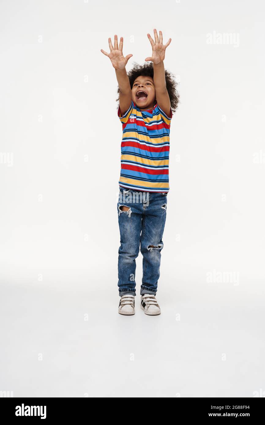 Happy preschooler african boy standing over white wall, having fun ...