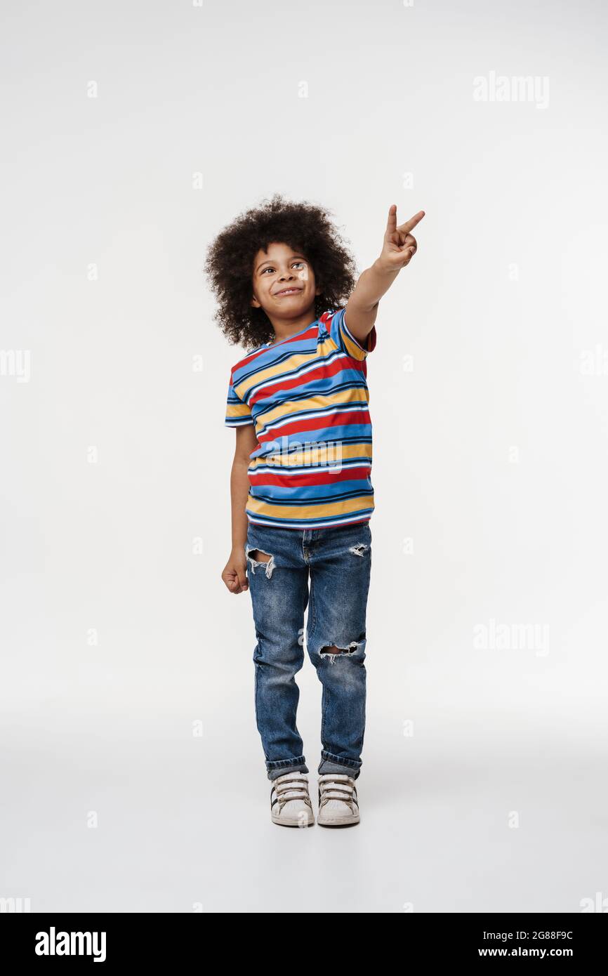 Happy preschooler african boy standing over white wall, having fun ...