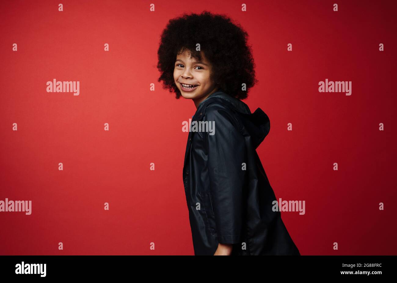 Happy preschooler african boy wearing coat standing over red wall ...