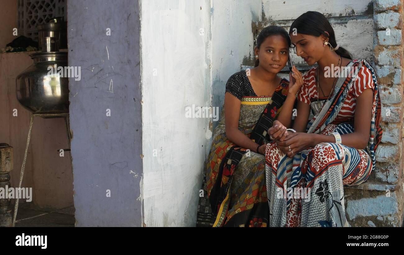Two young Indian females in traditional clothes talking on smartphone ...