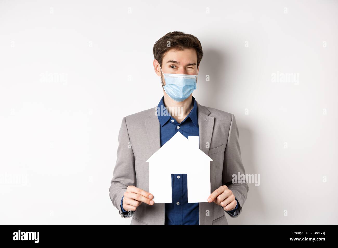 Real estate and covid-19 concept. Cheerful young man in medical mask ...