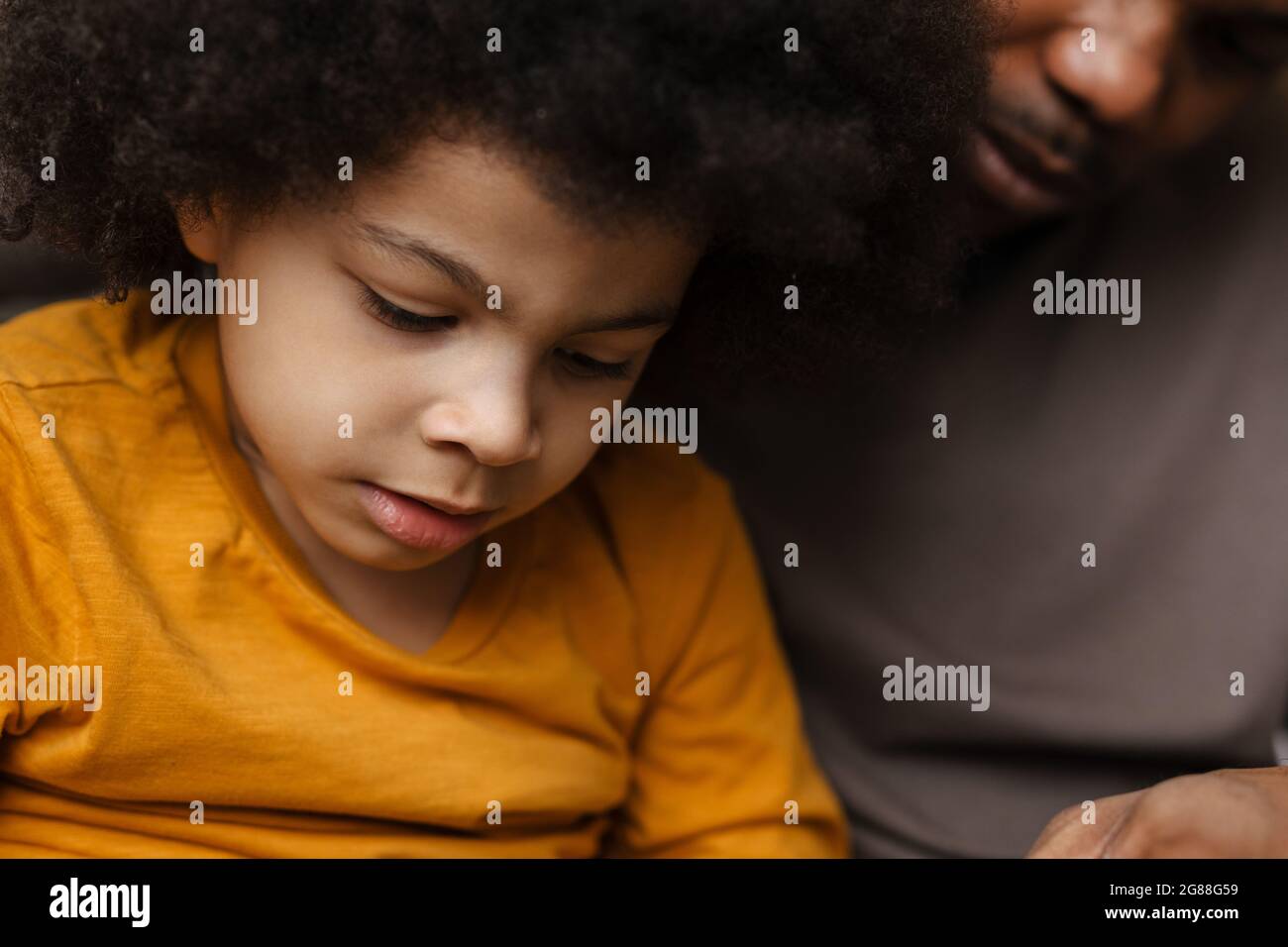Black father and son looking downwards while sitting indoors Stock ...