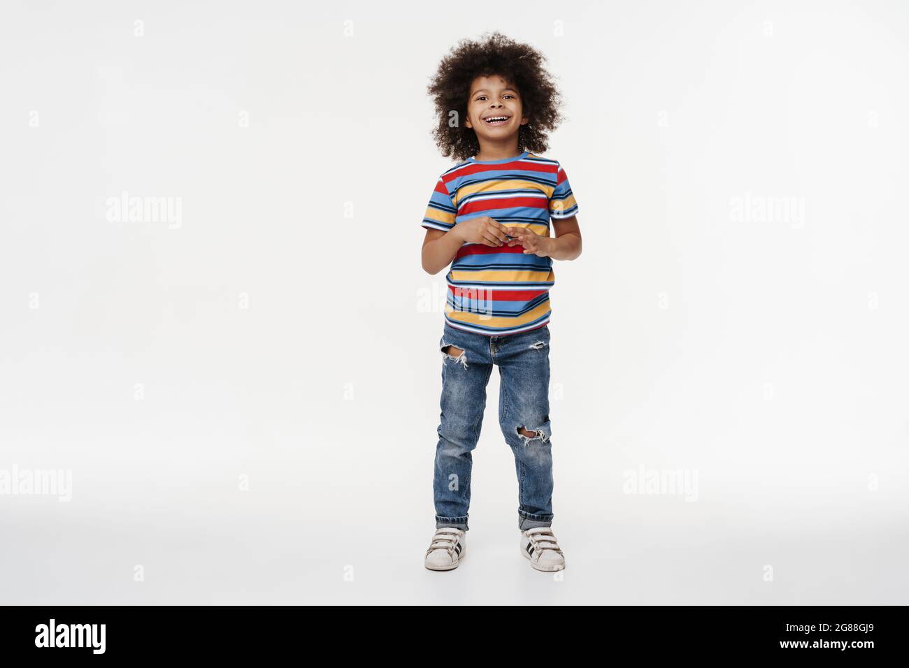 Happy preschooler african boy standing over white wall, having fun ...