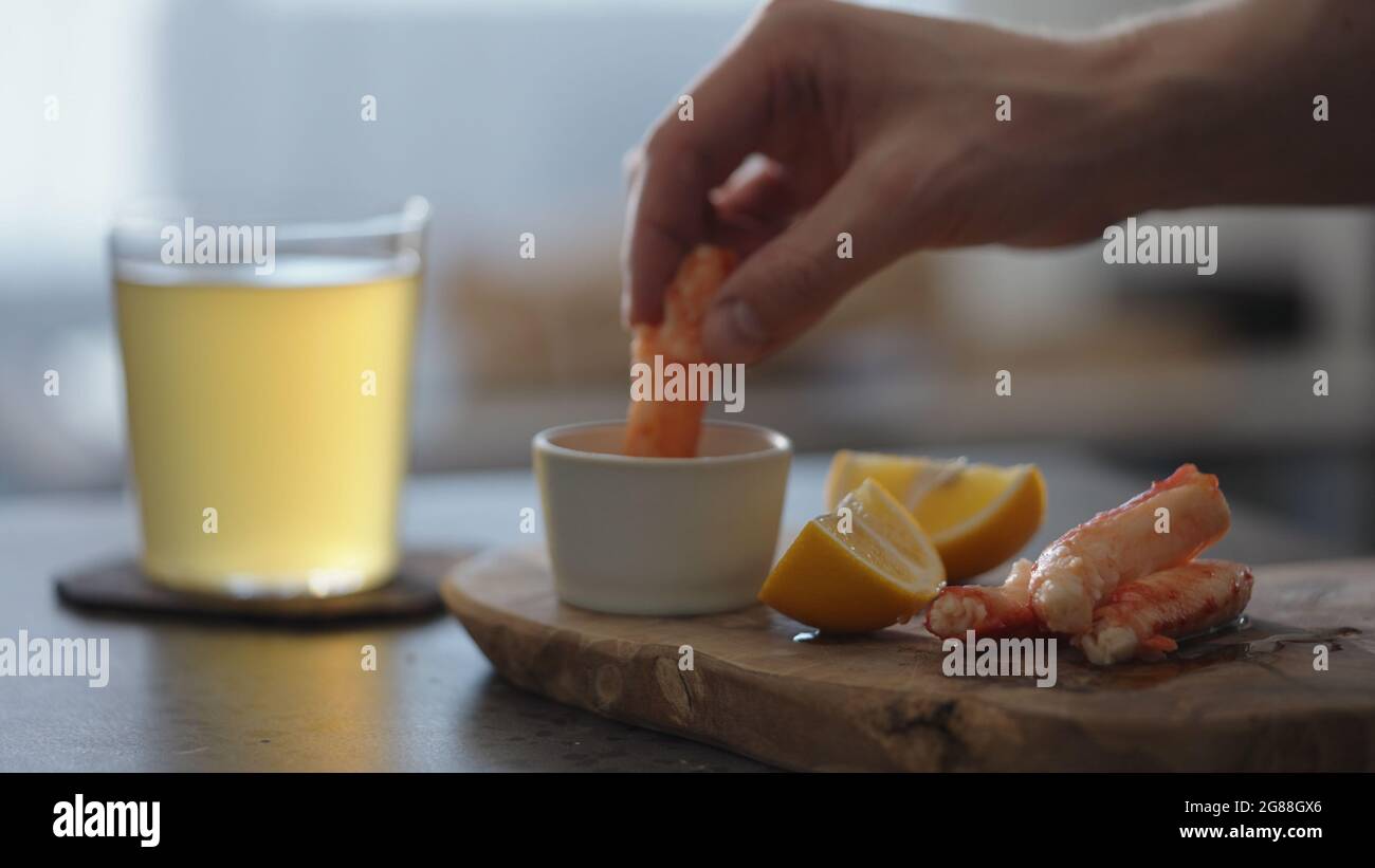 Man dip crab leg into pesto sauce with ginger beer on background, wide ...