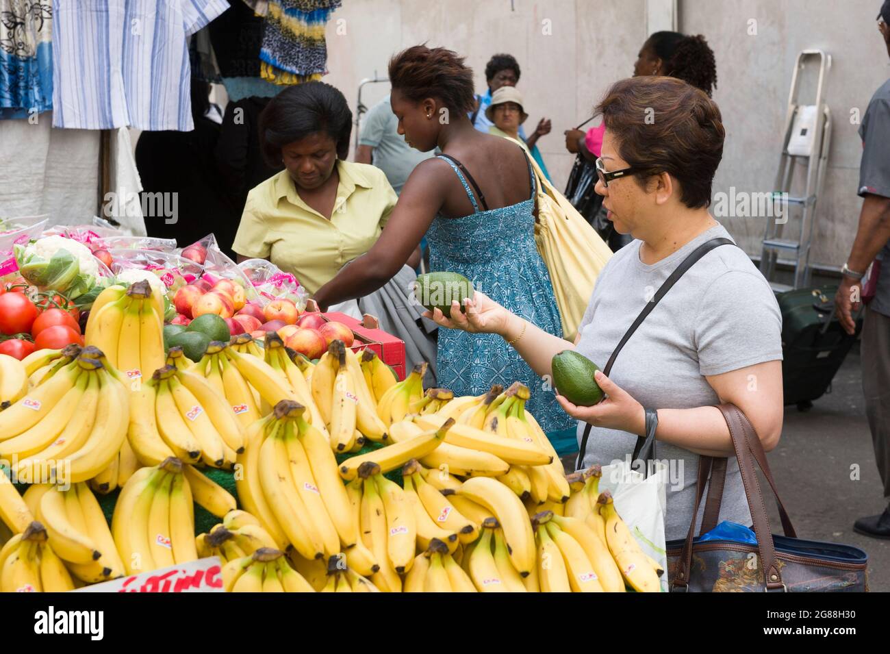 Multi ethic shoppers at a fruit and vegetables stall, Brixton market ...