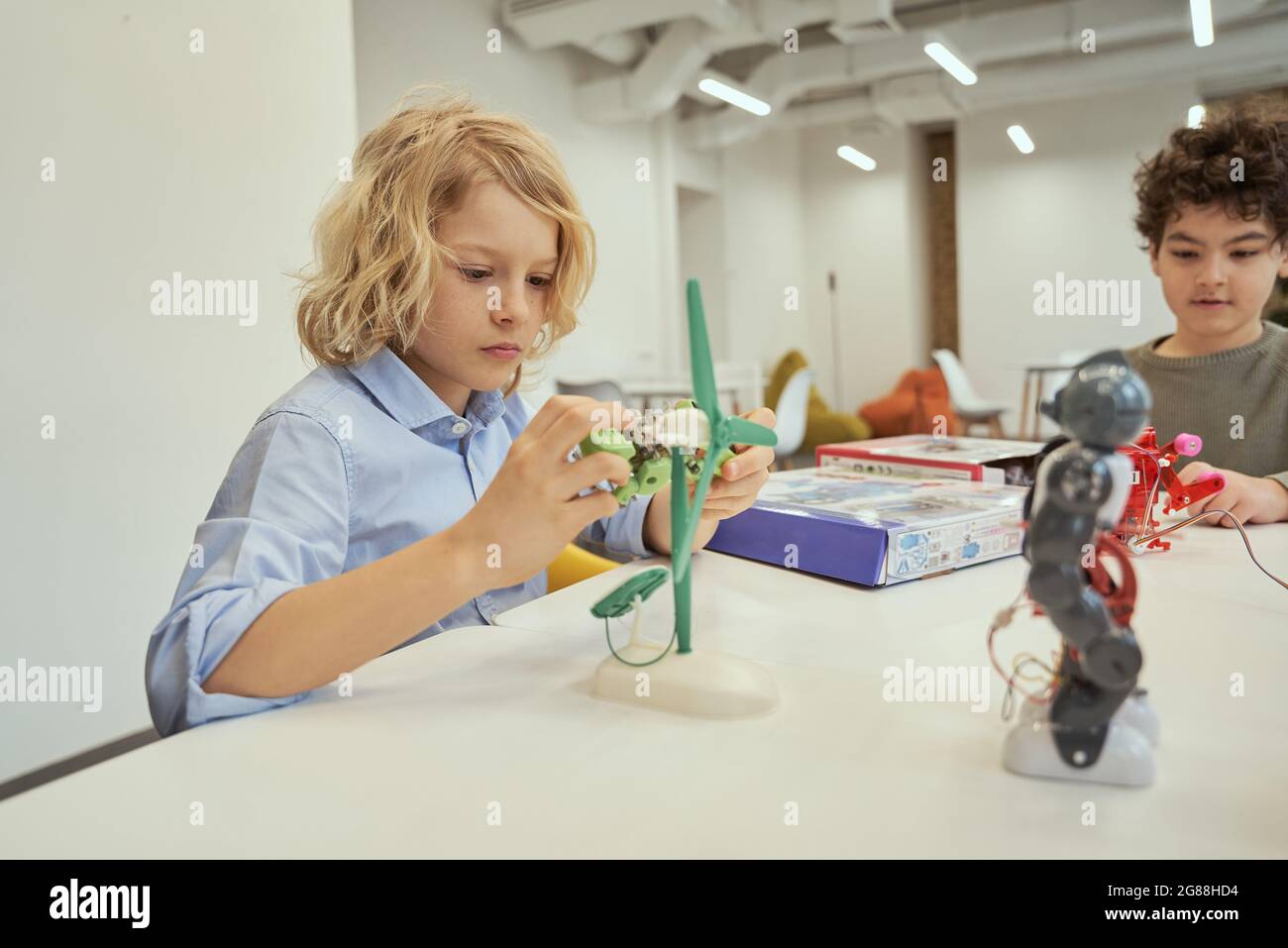 Create things. Caucasian boy examining technical toy while sitting at ...