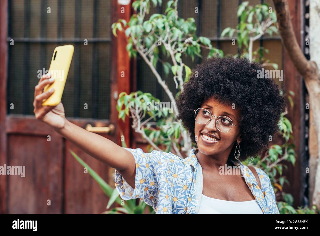 african attractive woman raising her arm with her telephone to take a ...