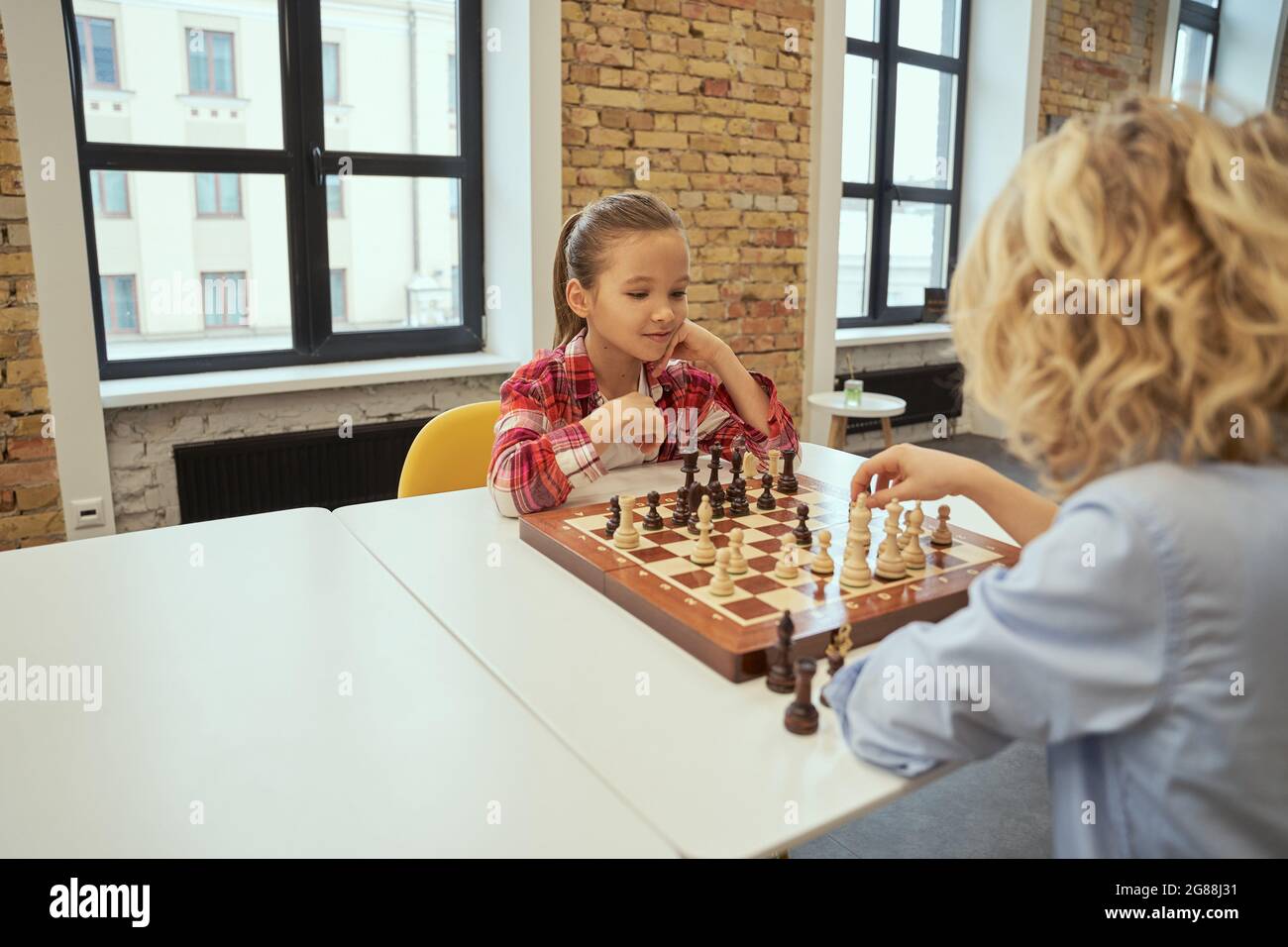 Opponent at the board. Beautiful little girl planning her move while ...