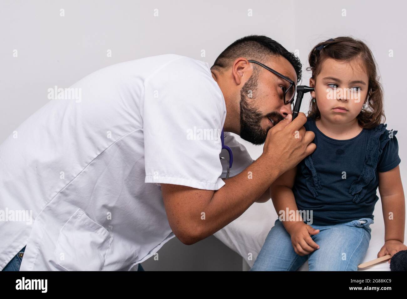 Caucasian thirty-year-old pediatrician examining the ears of his ...