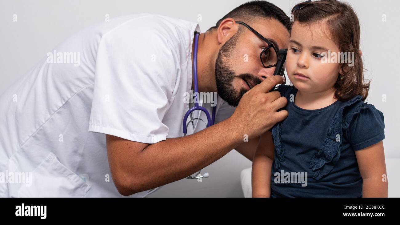 Caucasian thirty-year-old pediatrician examining the ears of his ...