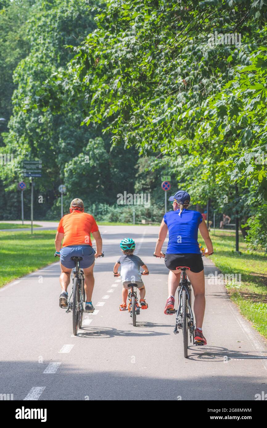 Family with kid or child cycling on the road bike in a park in summer ...