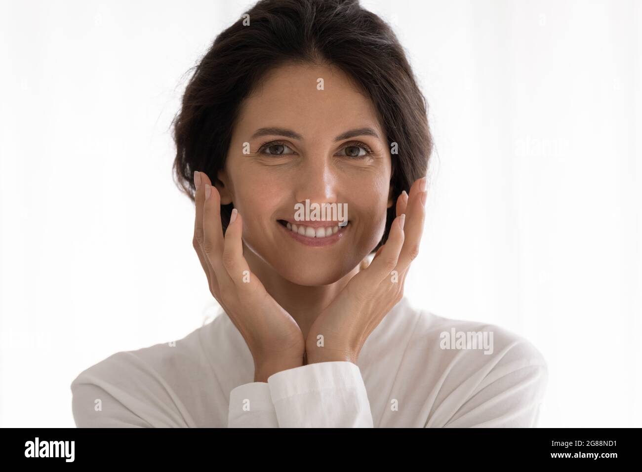 Pretty young latin woman looking at camera smiling touching cheeks Stock Photo - Alamy