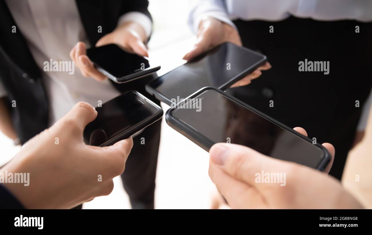 Business group standing in circle, holding similar mobile phones ...