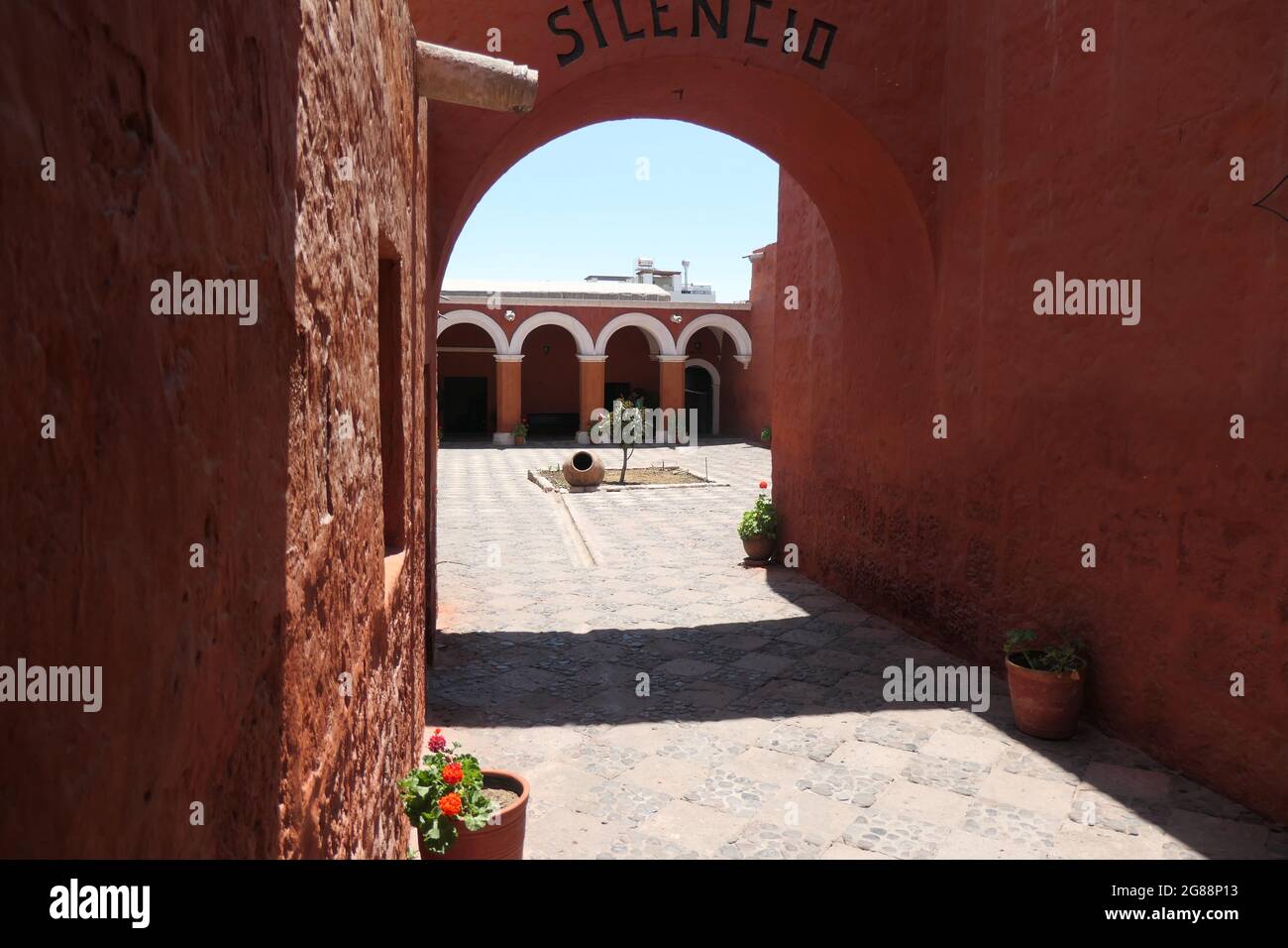 Arch in wall Arequipa Peru jug bowl arched sign plant flowers red old ...
