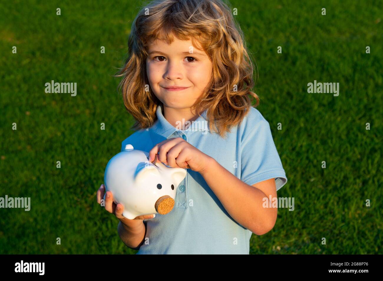 Boy putting money into a piggy bank. Portrait of a joyful cute little ...