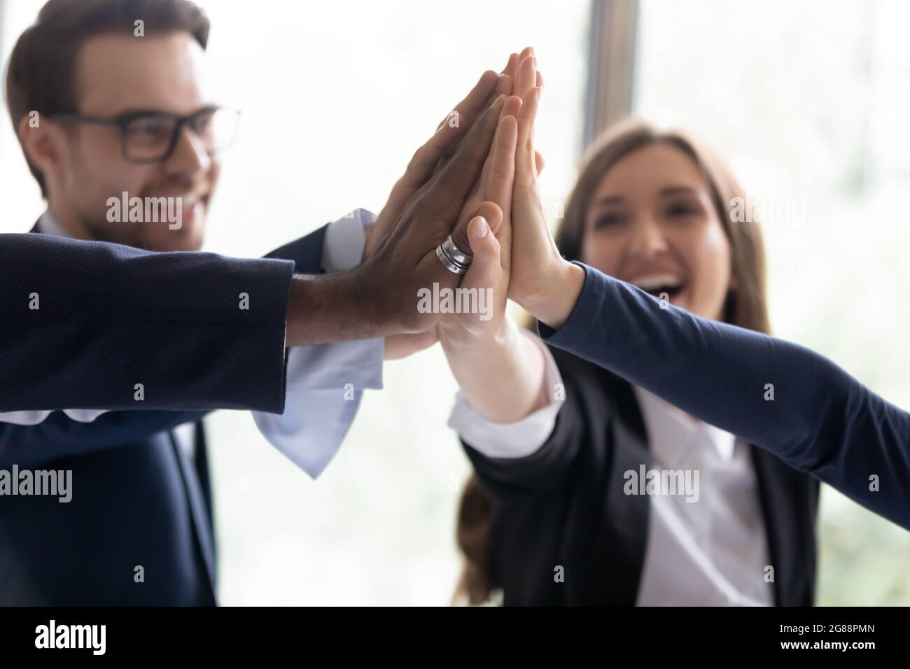 Excited office employees giving group high five Stock Photo - Alamy