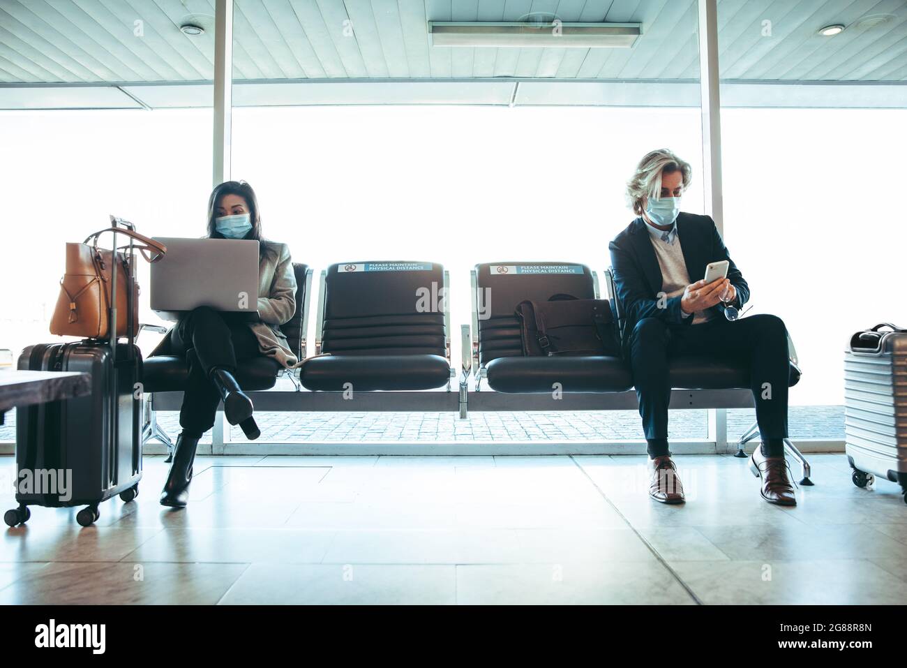 People wearing face masks sitting on chairs with social distance at ...