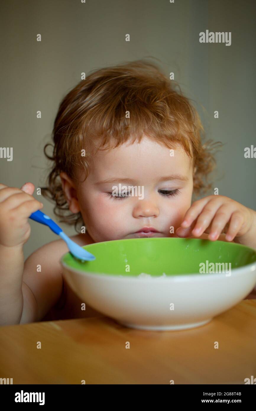 Kid baby eat soup in the kitchen with dishes and spoon. Child nutrition ...