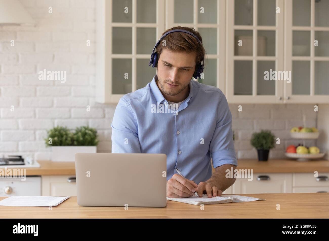 Young male in headset look on pc screen take notes Stock Photo - Alamy