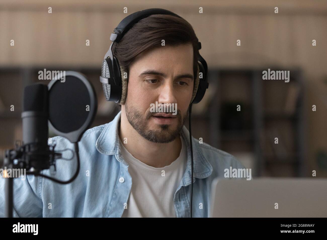Concentrated young man singing song looking at computer screen Stock ...