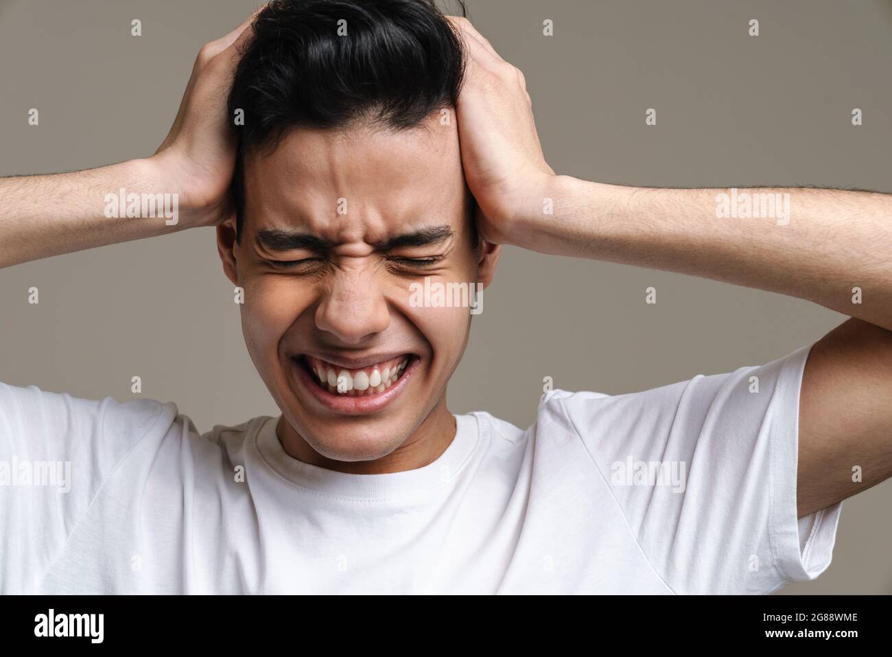 Unhappy hispanic man with headache frowning and holding his head ...