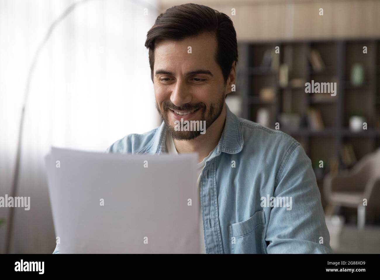 Happy millennial generation man reading paper document Stock Photo - Alamy