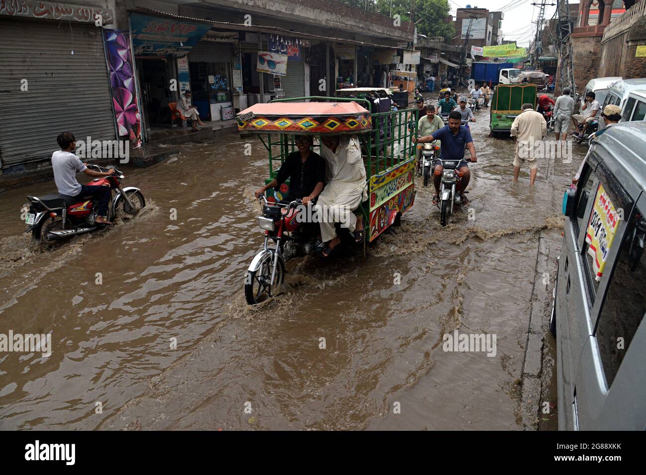 Lahore, Pakistan. 18th July, 2021. Pakistani commuters wade through a ...