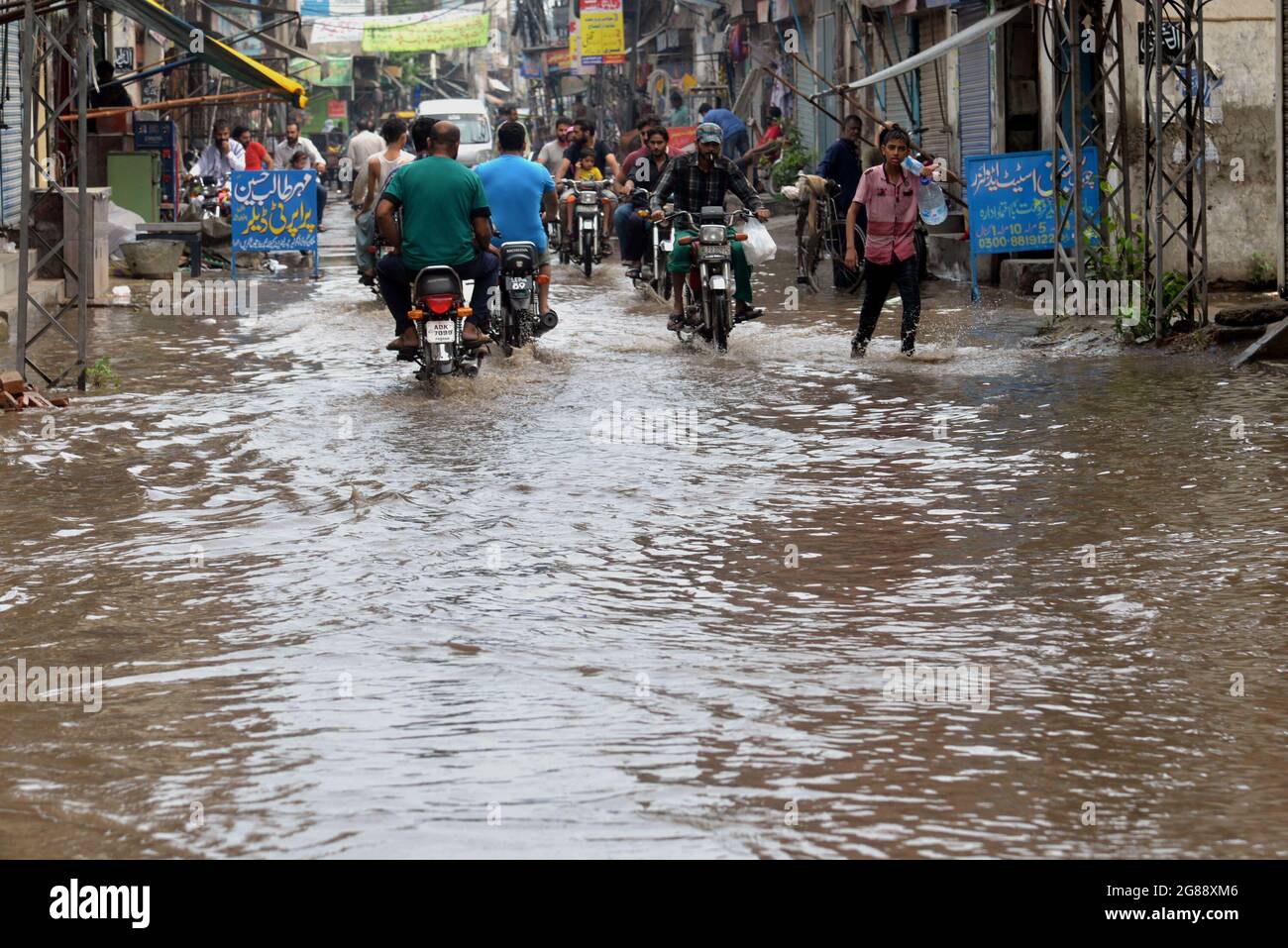 Lahore, Pakistan. 18th July, 2021. Pakistani commuters wade through a ...