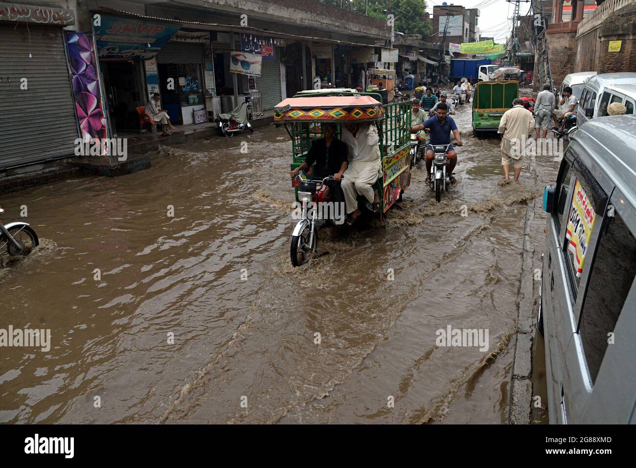 Lahore, Pakistan. 18th July, 2021. Pakistani commuters wade through a ...