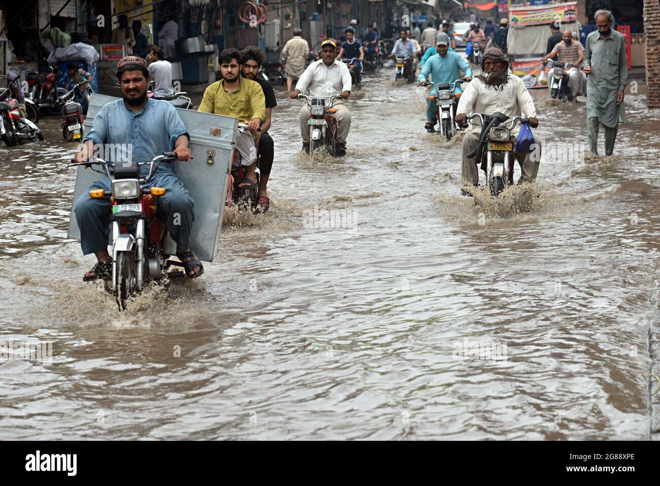 Lahore, Pakistan. 18th July, 2021. Pakistani commuters wade through a ...