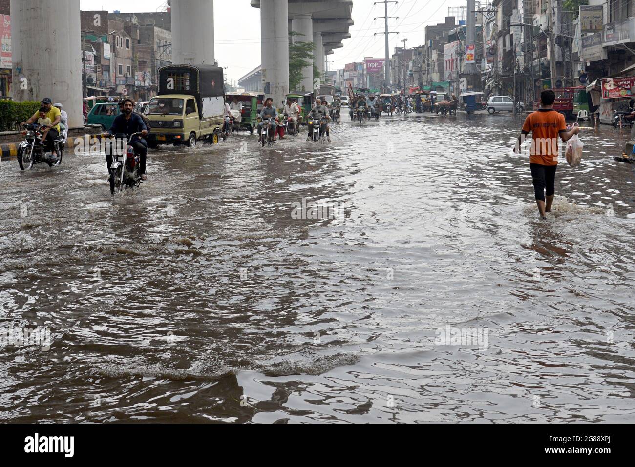 Lahore, Pakistan. 18th July, 2021. Pakistani commuters wade through a ...