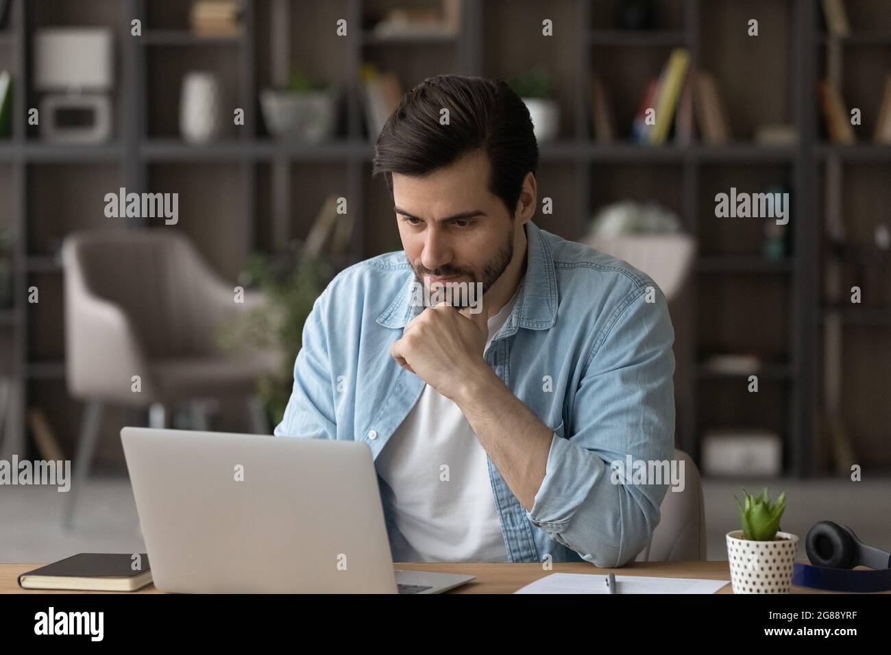 Concentrated millennial man working on computer at home office Stock ...