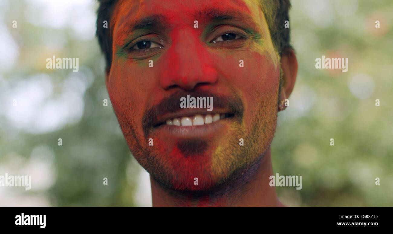 A cheerful Indian guy with painted face is attending the Holi, Festival ...