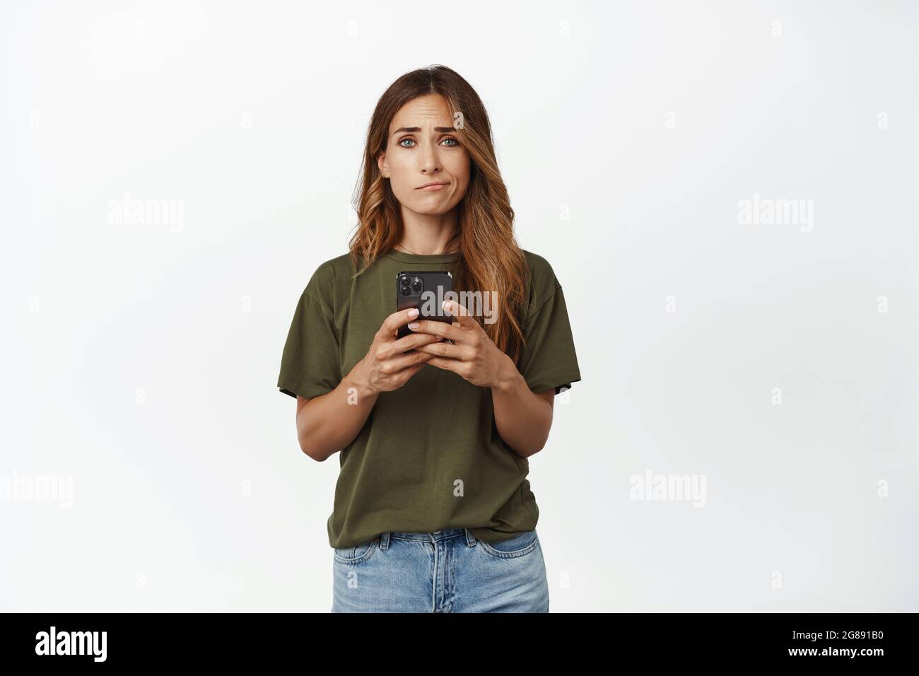 Disappointed and upset middle aged woman holding smartphone, furrow ...