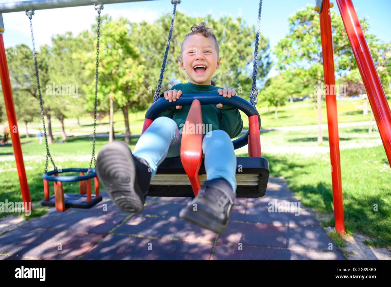 Cute young boy playing on swing in a park having fun - Funny, joy ...