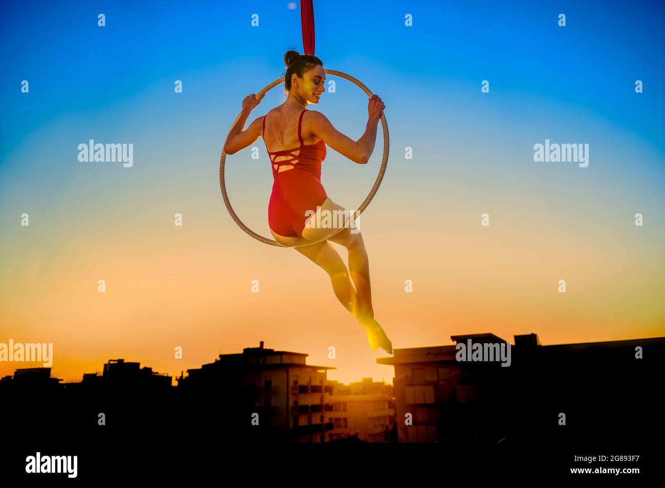 Aerial acrobat in a hoop in sunset on the skyline city - Outdoor ...