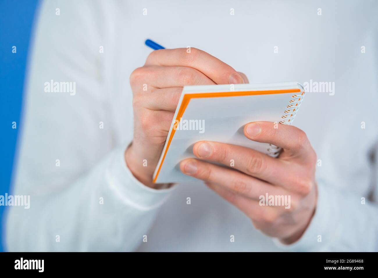 Man hands making notes in planner, caucasian guy holding pen. He writes ...