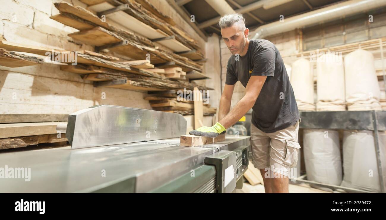 Carpenter processes wood in a furniture workshop. Woodworking and ...