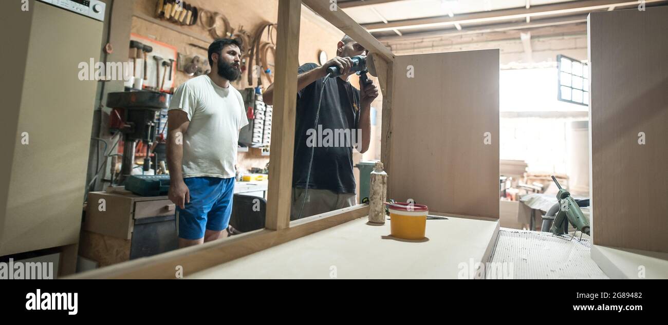 Craftsman is using an electric sander, to smoothen the wood texture ...