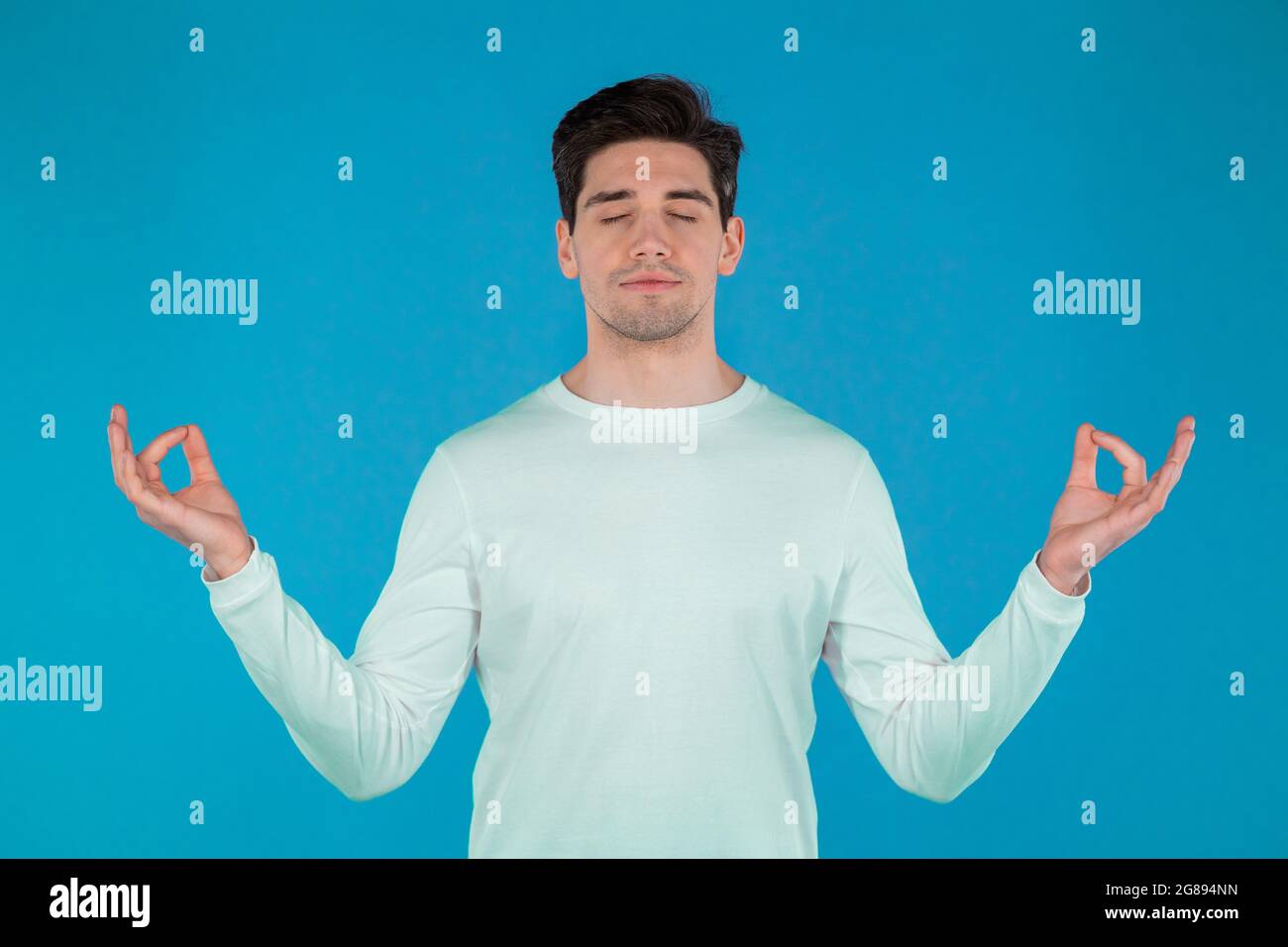 Calm man in white wear relaxing, meditating. He calms down, breathes ...