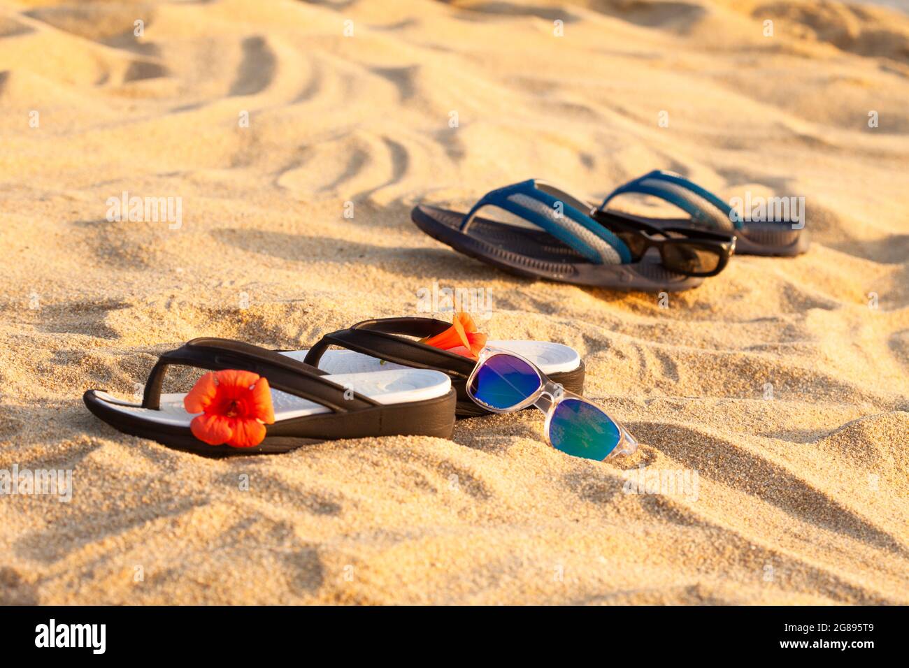 Male and female slippers and sun glasses on a beach. Concept for a ...