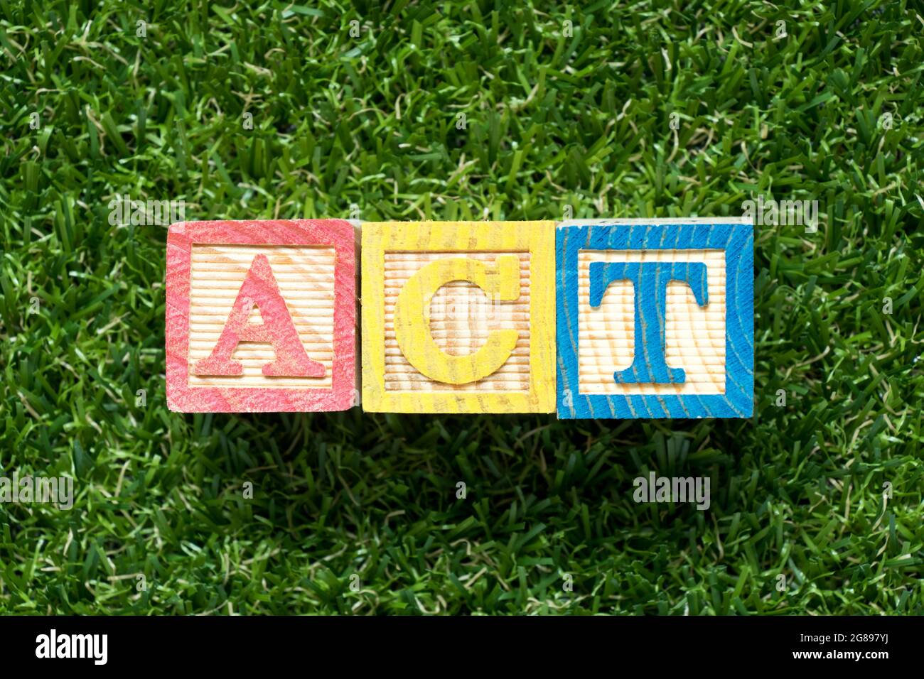 Color wood block in word act on artificial green grass background Stock ...
