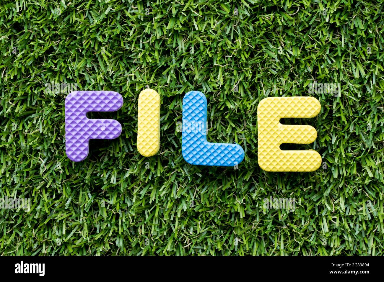 Color alphabet letter in word file on artificial green grass background ...