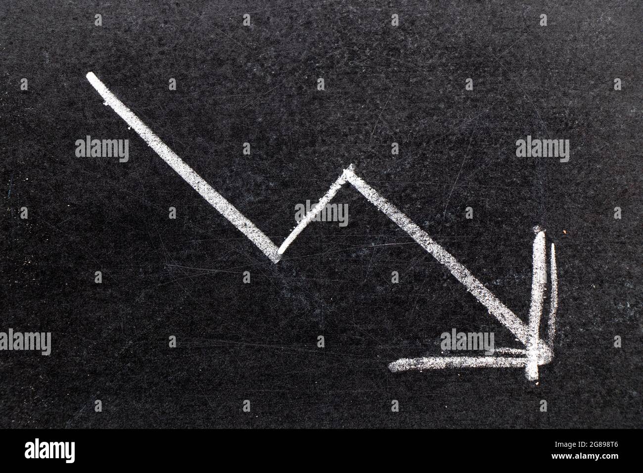 White chalk hand drawing in arrow down shape on black board background ...