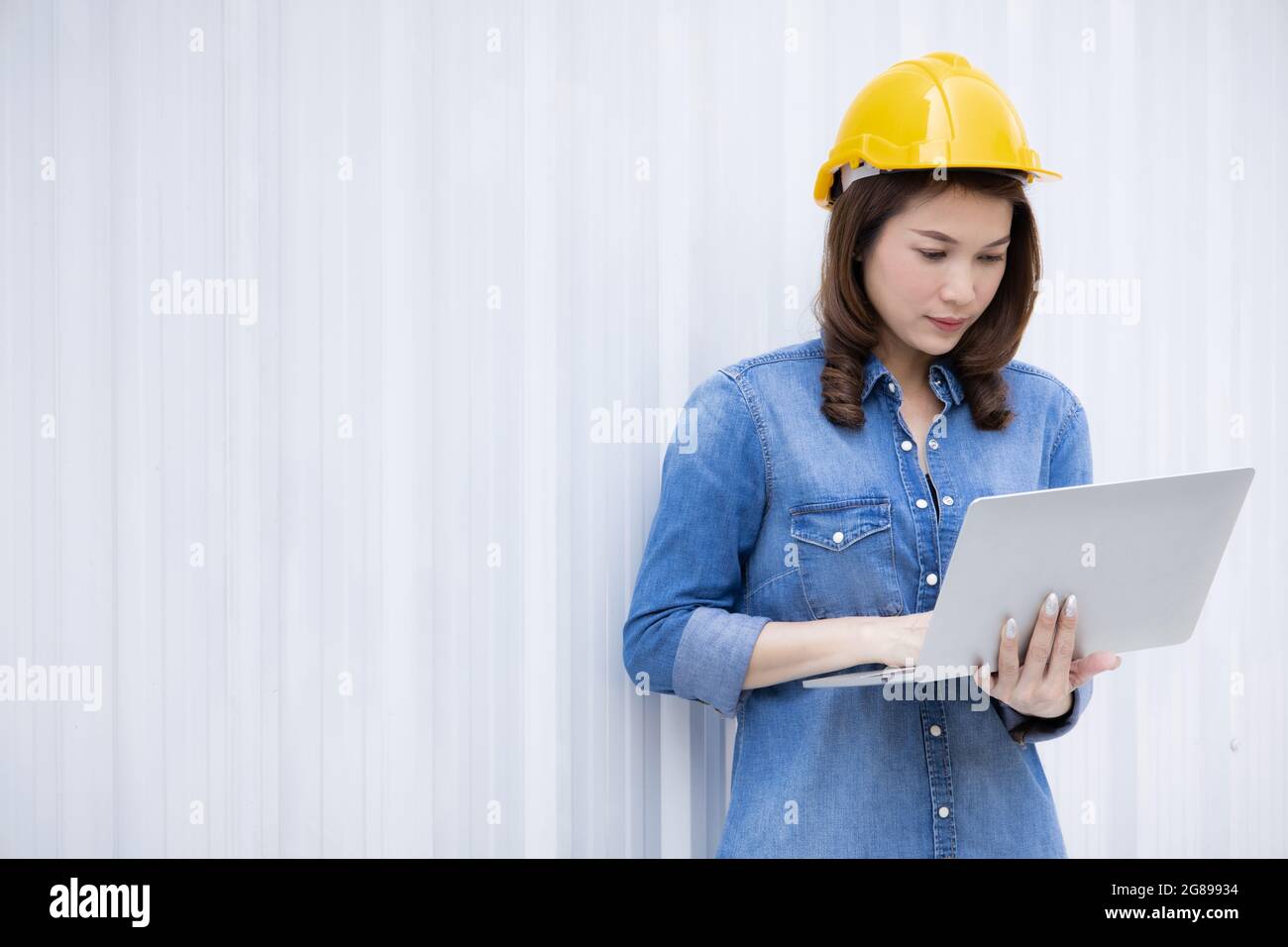 Beautiful Asian female engineer in jeans dress wearing yellow safety ...