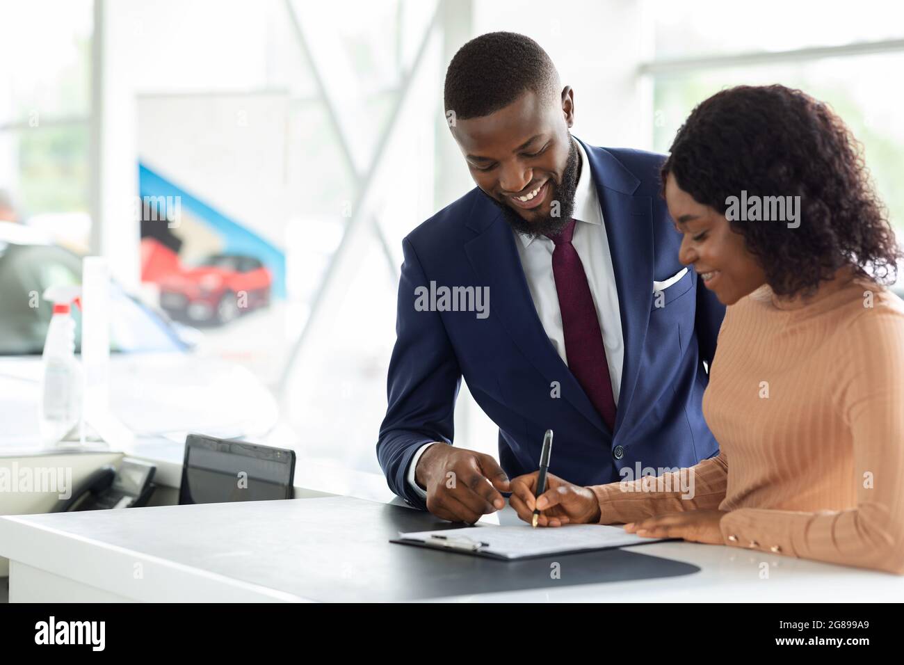 Black Woman Buying New Car, Signing Papers With Salesman In Dealership ...