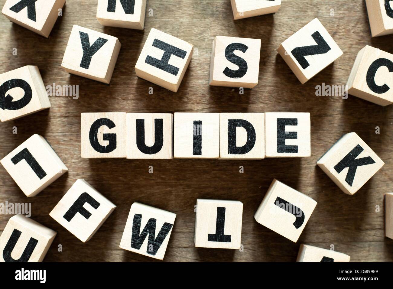 Letter block in word guide with another block on wood background Stock ...