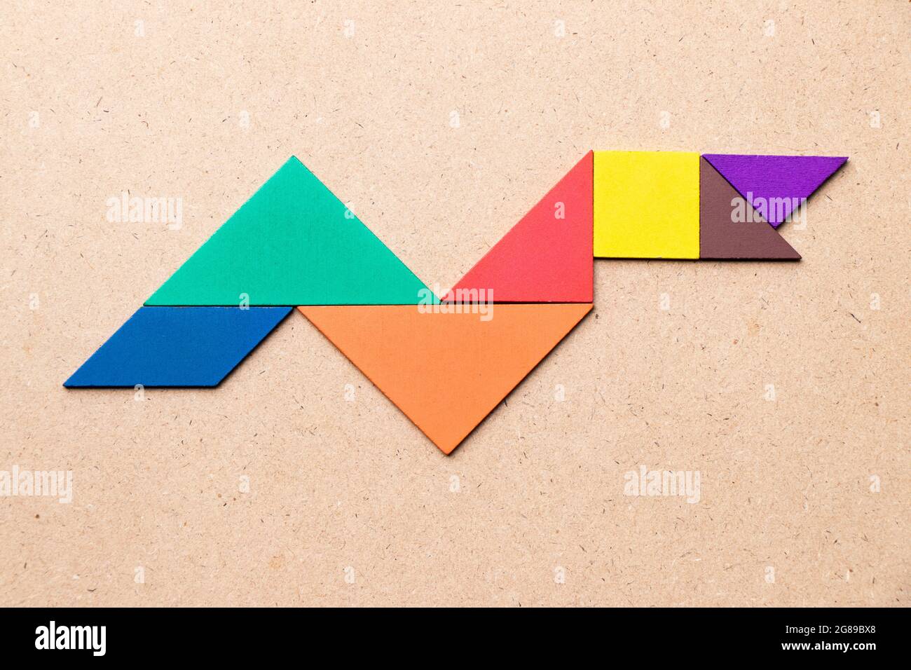 Color tangram puzzle in snake or dragon shape on wood background Stock ...
