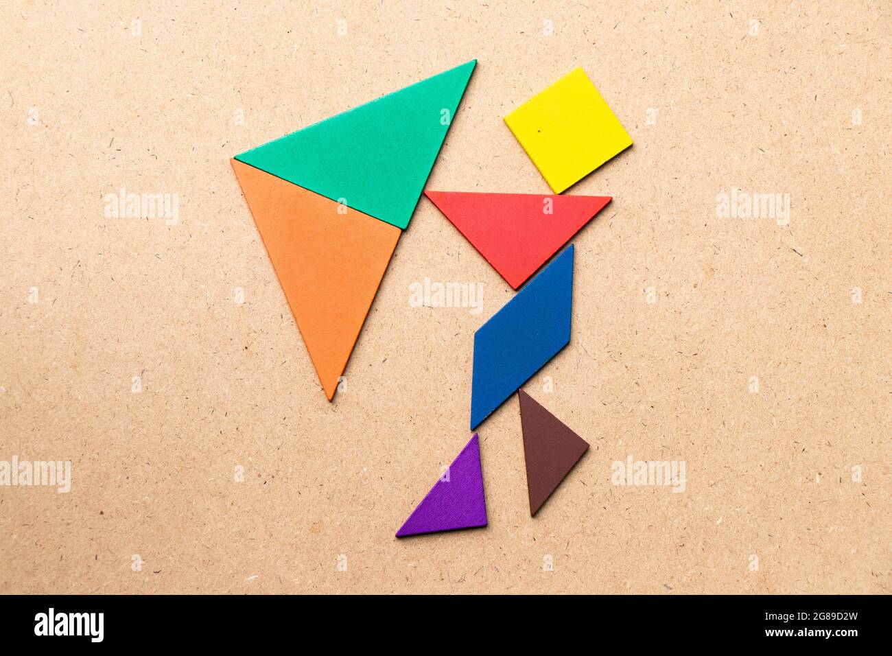 Color tangram puzzle in man hold umbrella shape on wood background ...
