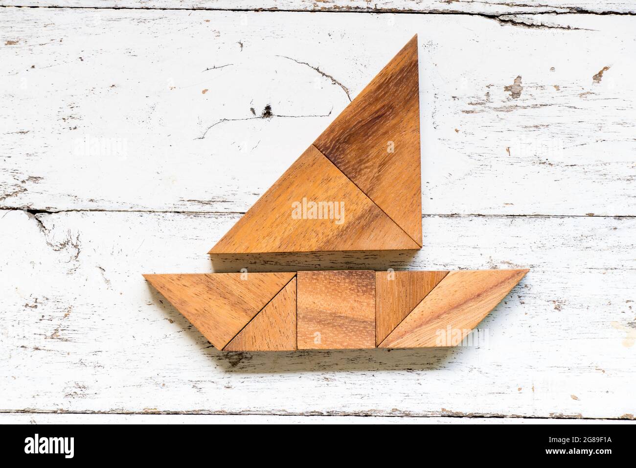 Tangram puzzle in boat or yacht shape on old white wood background ...